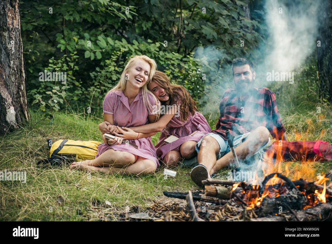 Telling jokes by bonfire. Laughing friends camping in woods. Smoke of ...