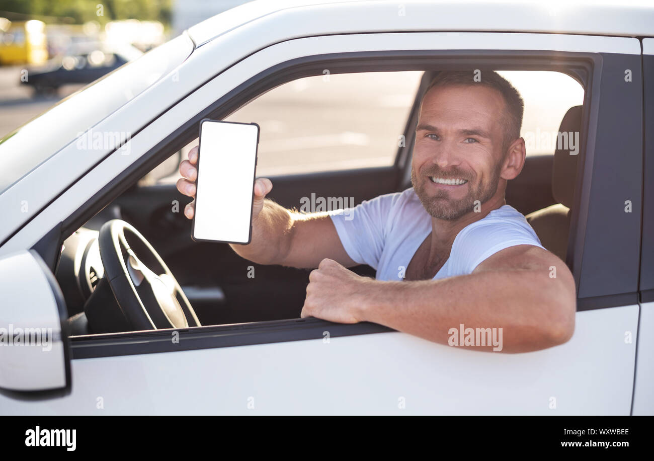 An attractive man in a car shows a smartphone Stock Photo - Alamy
