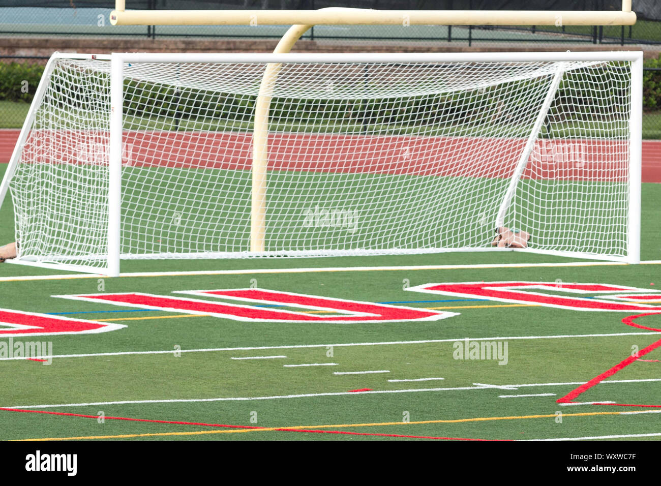 A new soccer goal on a new green turf field with red and white writing ...