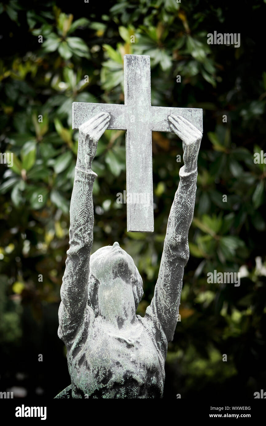 Old statue with cross on a grave in the Cimitero Monumentale ...
