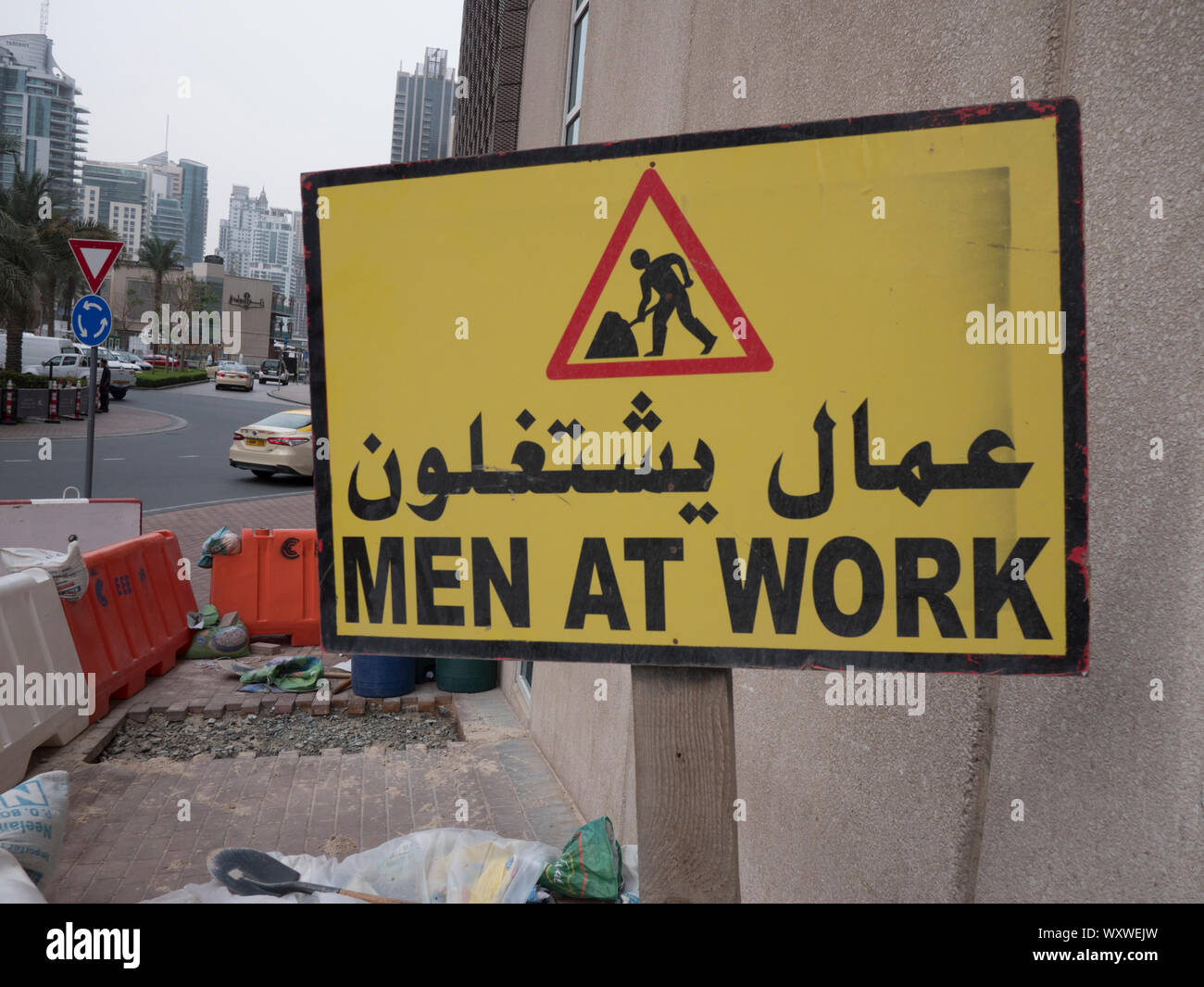 Men at Work sign at Dubai building construction works Stock Photo - Alamy