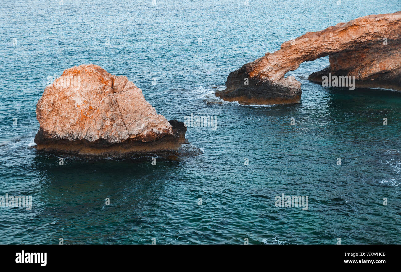 Natural stone arch known as the Love bridge and coastal rock ...
