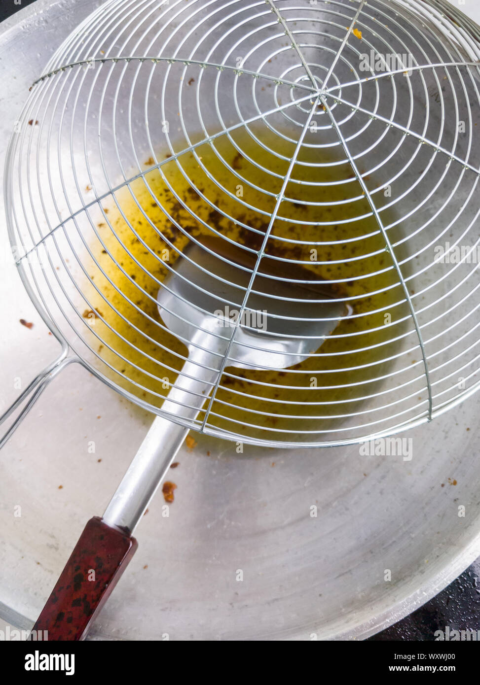 Large colander on the metal pan with the cooking oil after fried the ...