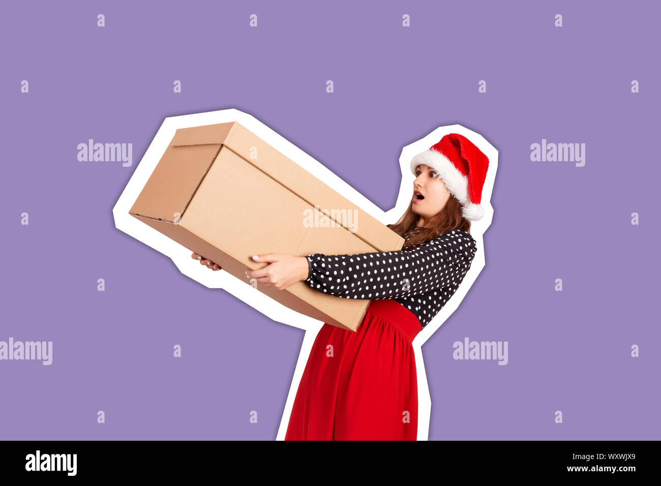 Portrait of excited surprised girl in dress holding big and heavy gift ...