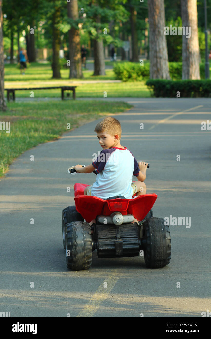 Boy riding big red toy car in park, back view Stock Photo - Alamy