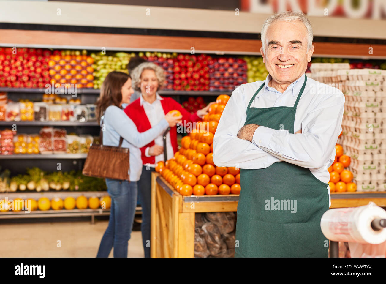 Senior as a successful salesman with crossed arms in the supermarket ...
