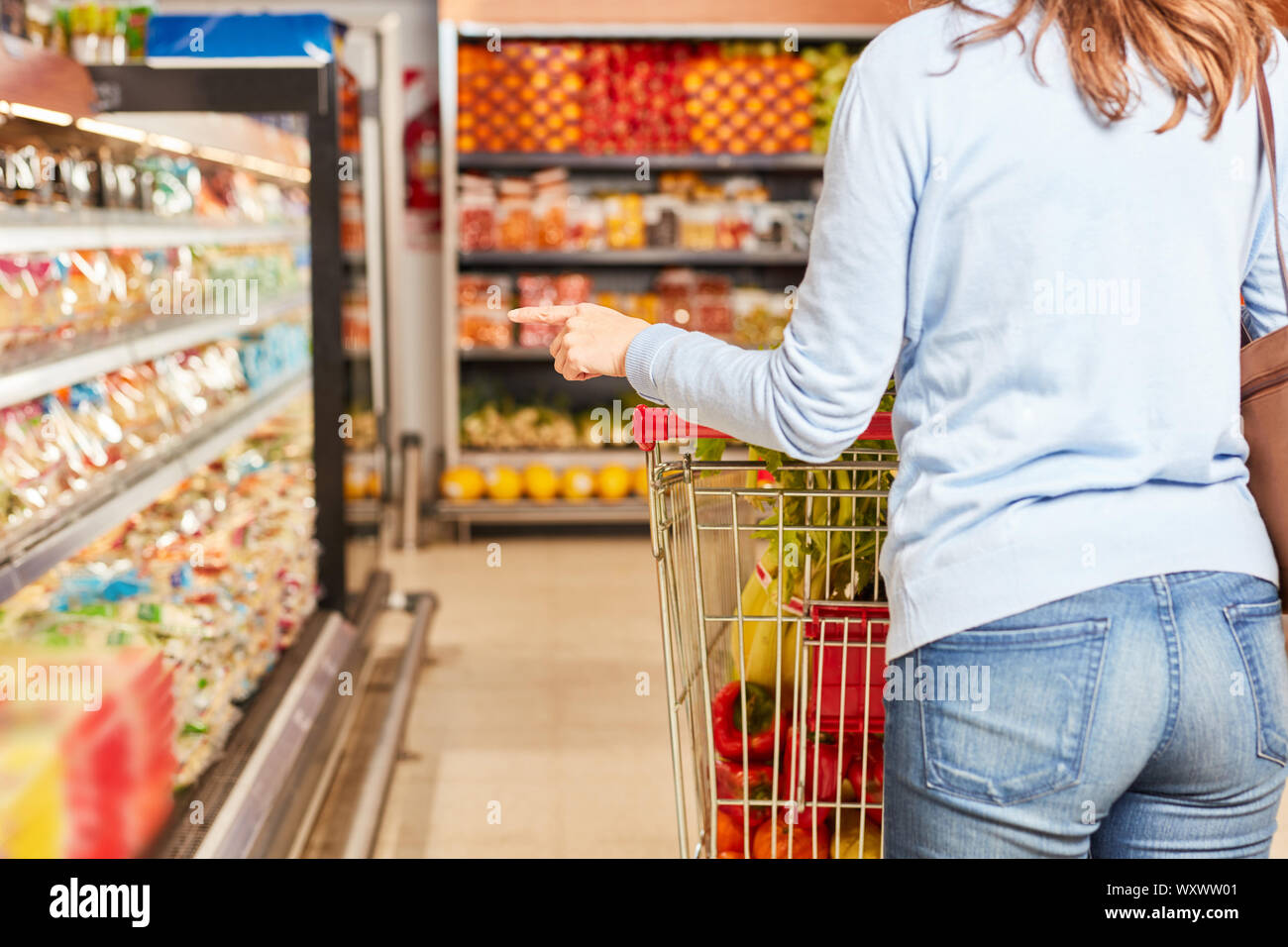 Customer shopping with cart on a refrigerated shelf in the supermarket ...