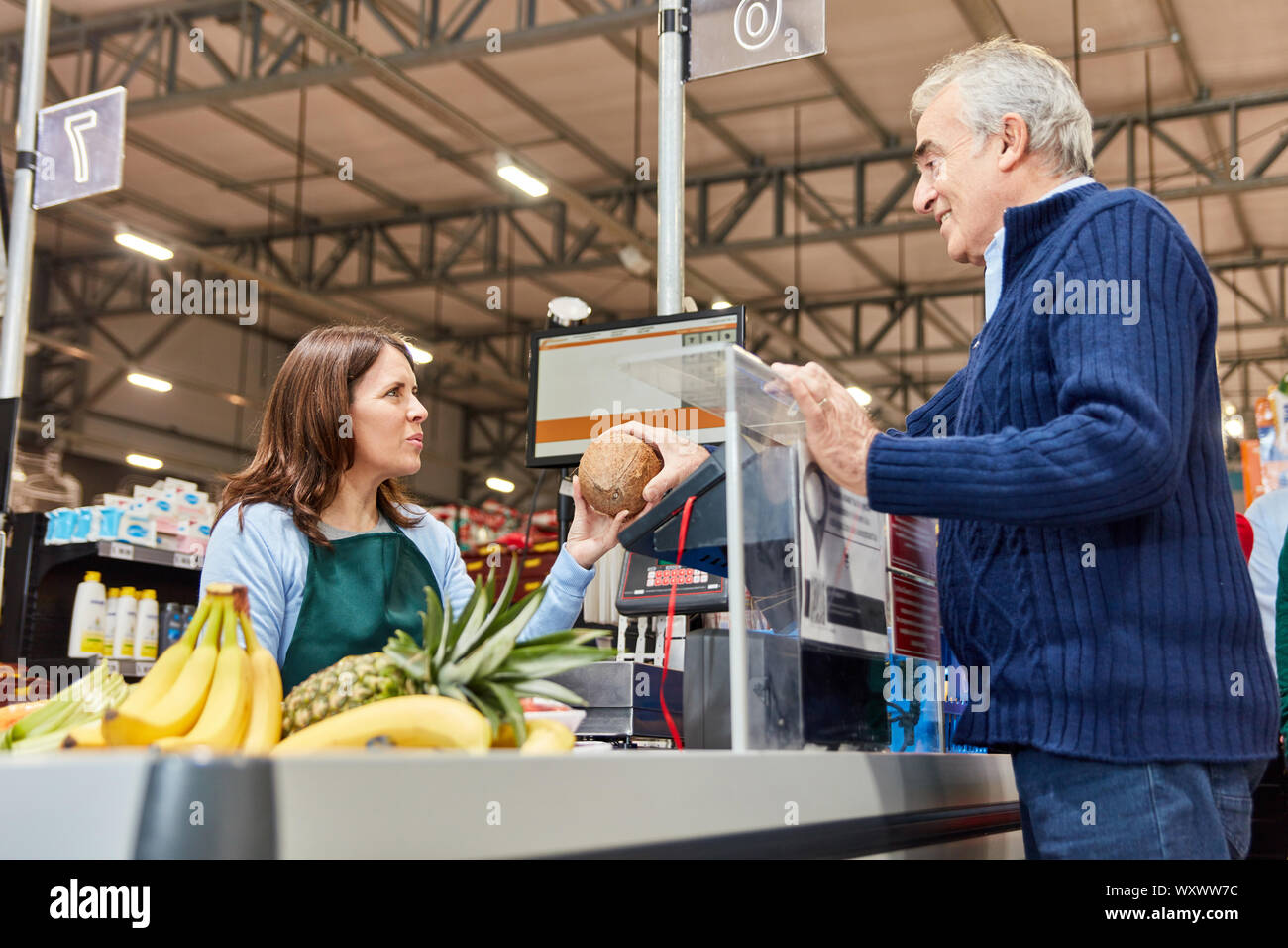 Senior as a customer paying at checkout in the supermarket or ...
