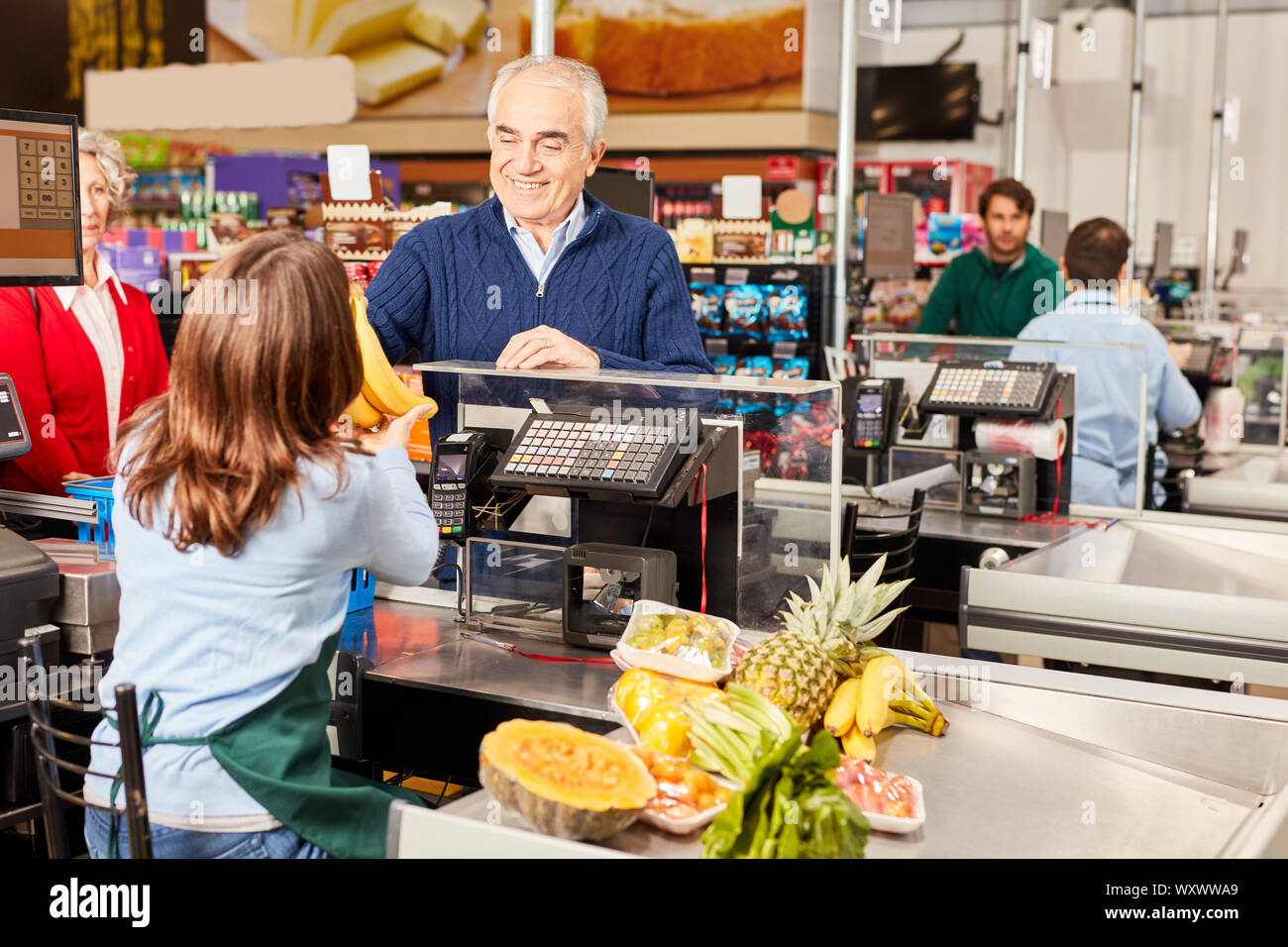 Senior as a customer at the supermarket cashier pays fruit at the ...