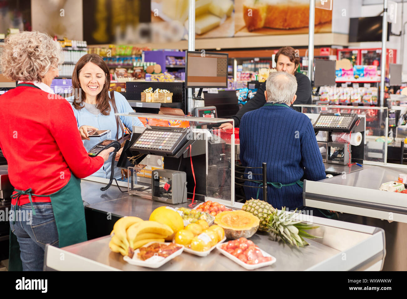 Customer at the supermarket cashier paying with NFC smartphone at the ...