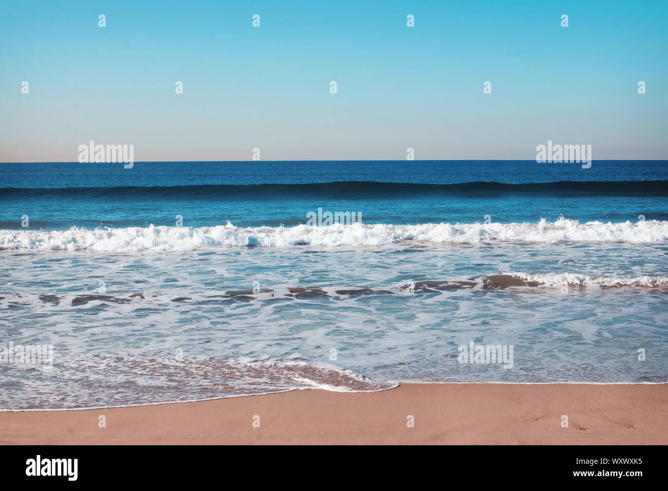 Empty ocean beach with small waves and foam Stock Photo - Alamy