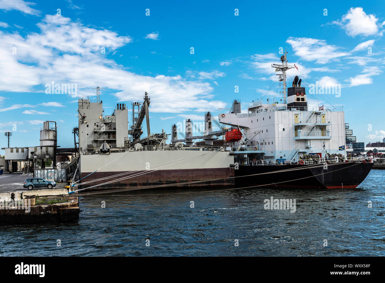 Cargo ship moored on the dock with industrial factories and warehouses ...