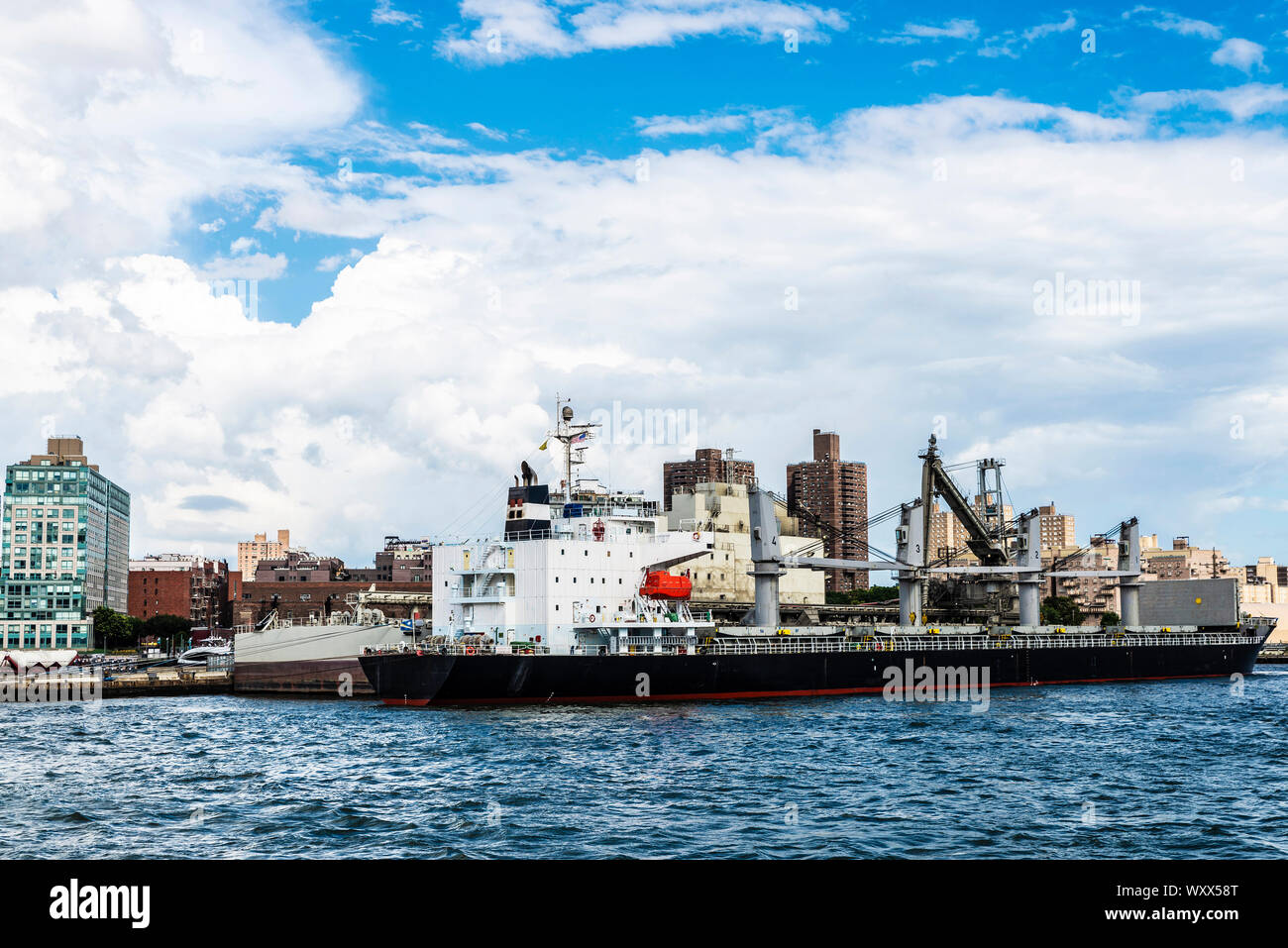 Cargo ship moored on the dock with industrial factories and warehouses ...