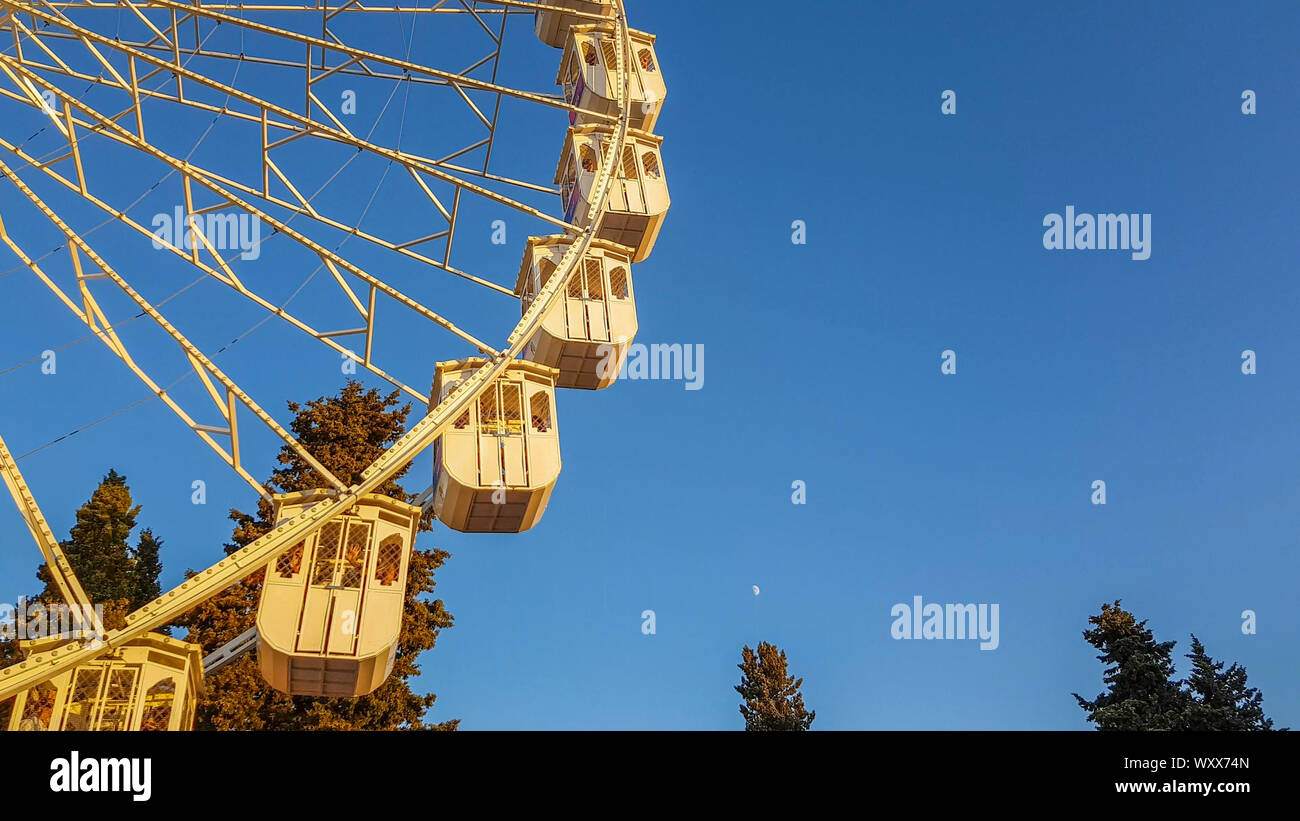 Ferris wheel at evening with moon visible Stock Photo - Alamy
