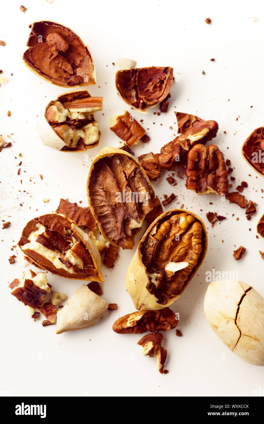 Cracked and opened pecan nuts and nuts in shell. Overhead wiew on white ...