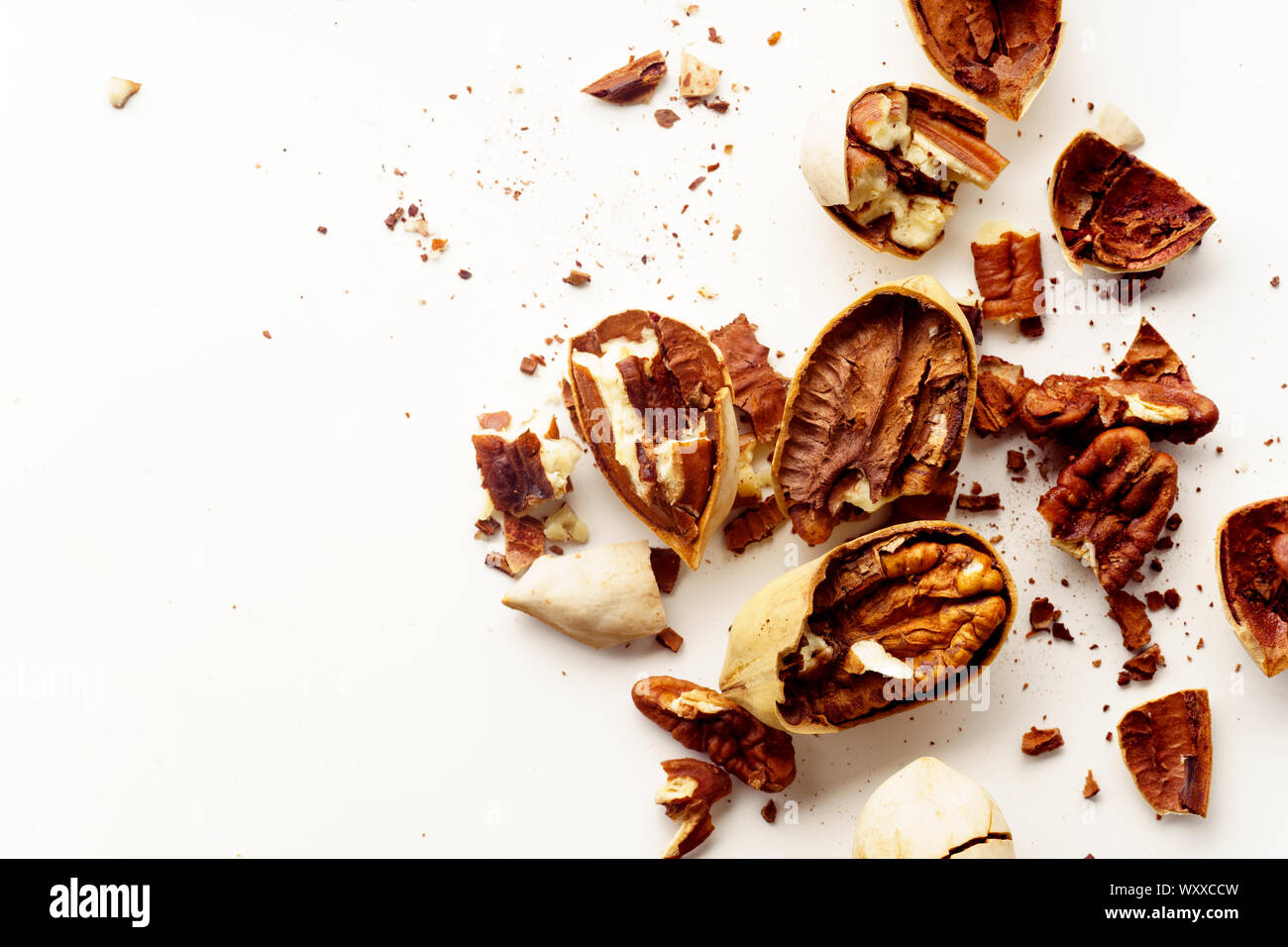 Cracked and opened pecan nuts and nuts in shell. Overhead wiew on white ...