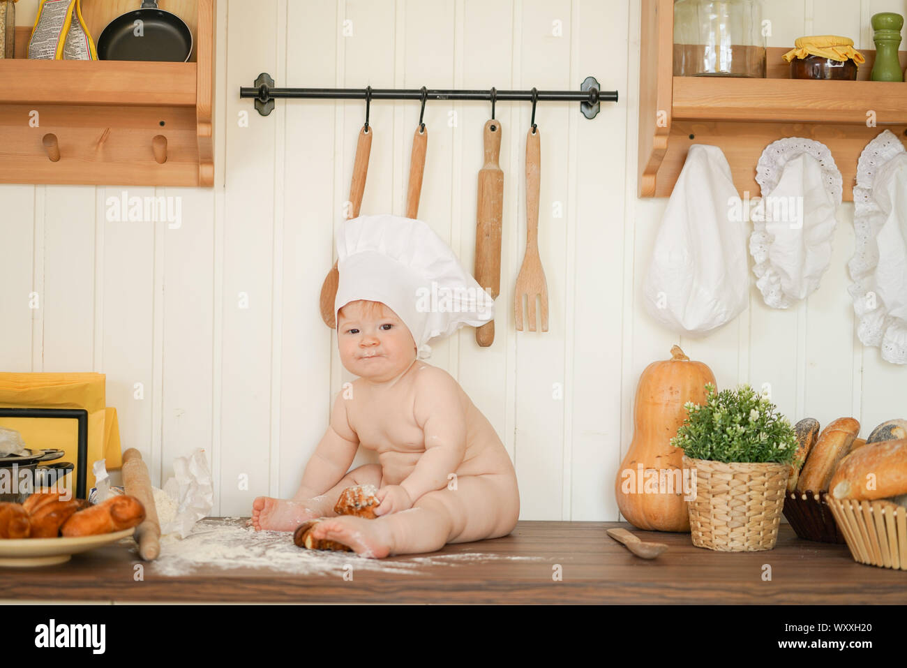 little baker child in chef hat at kitchen table alone with bread and ...