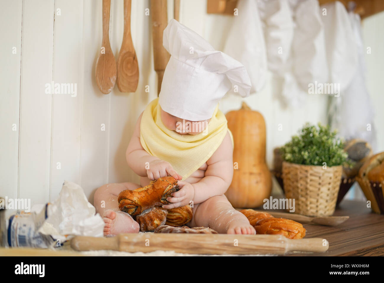 little baker child in chef hat at kitchen table alone with bread and ...