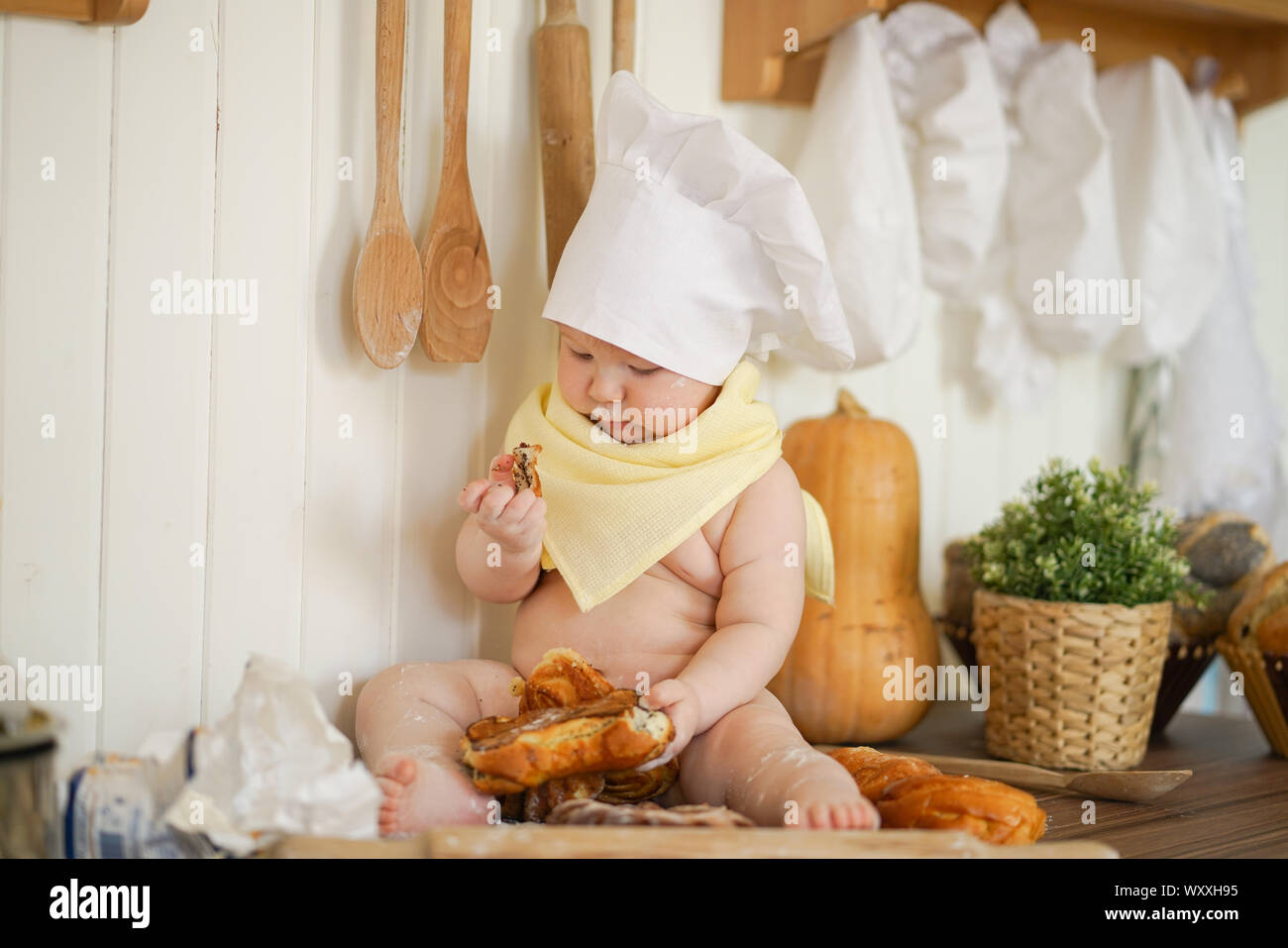 little baker child in chef hat at kitchen table alone with bread and ...