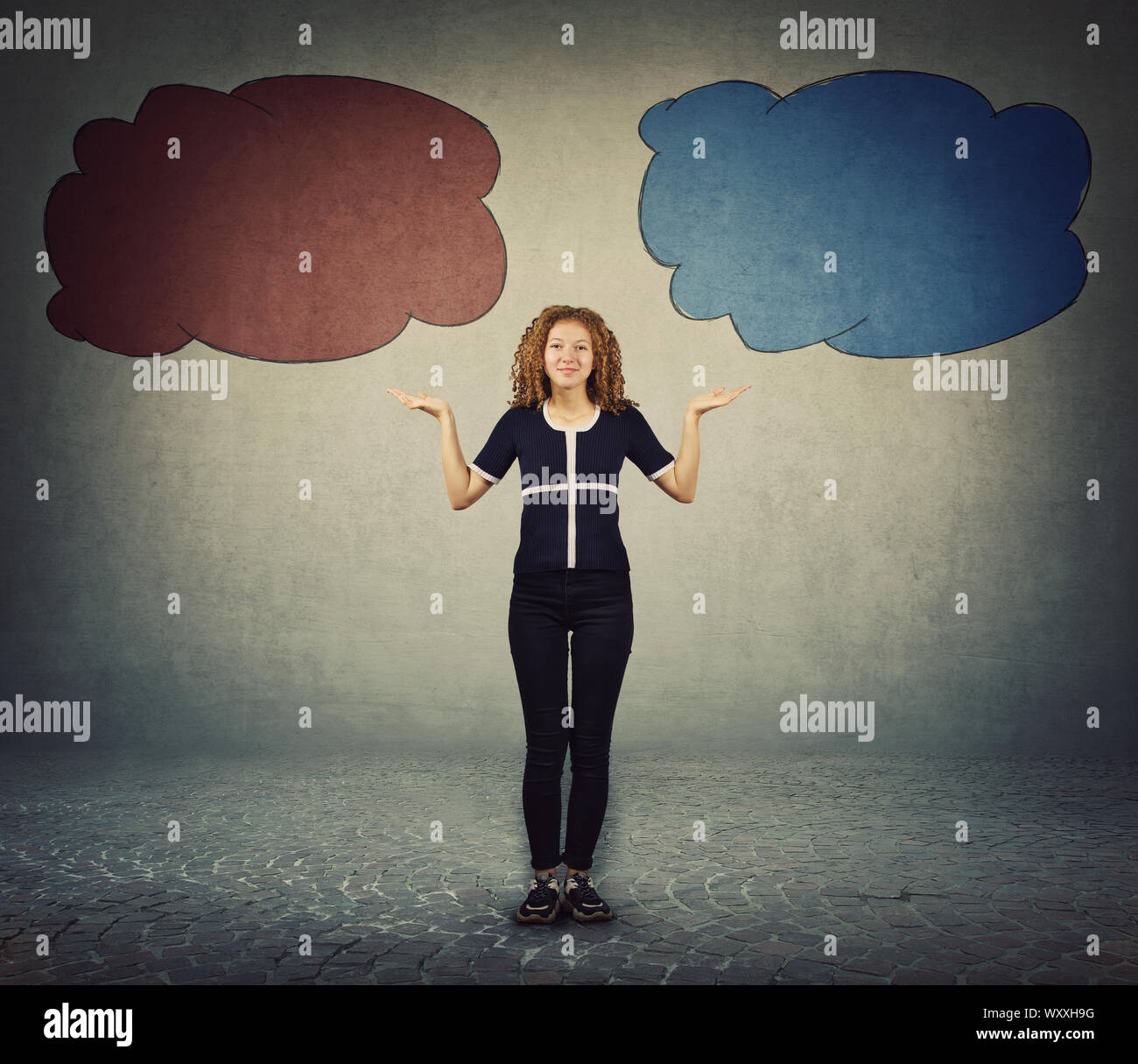 Cheerful teen girl balancing hands, spread arms gesture, giving two options to choose right or ...
