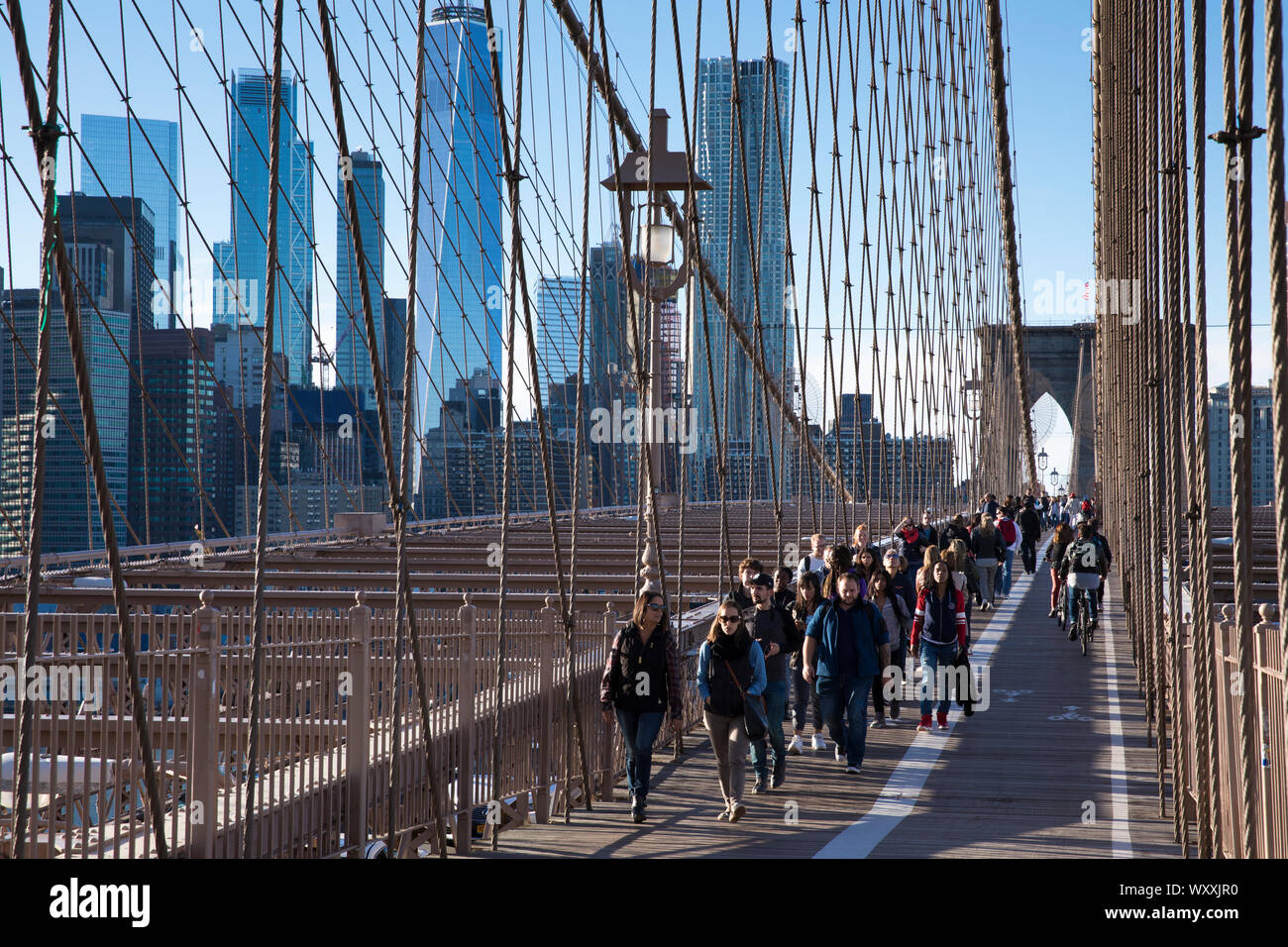 Tourists and local people stroll across Brooklyn Bridge from Manhattan ...
