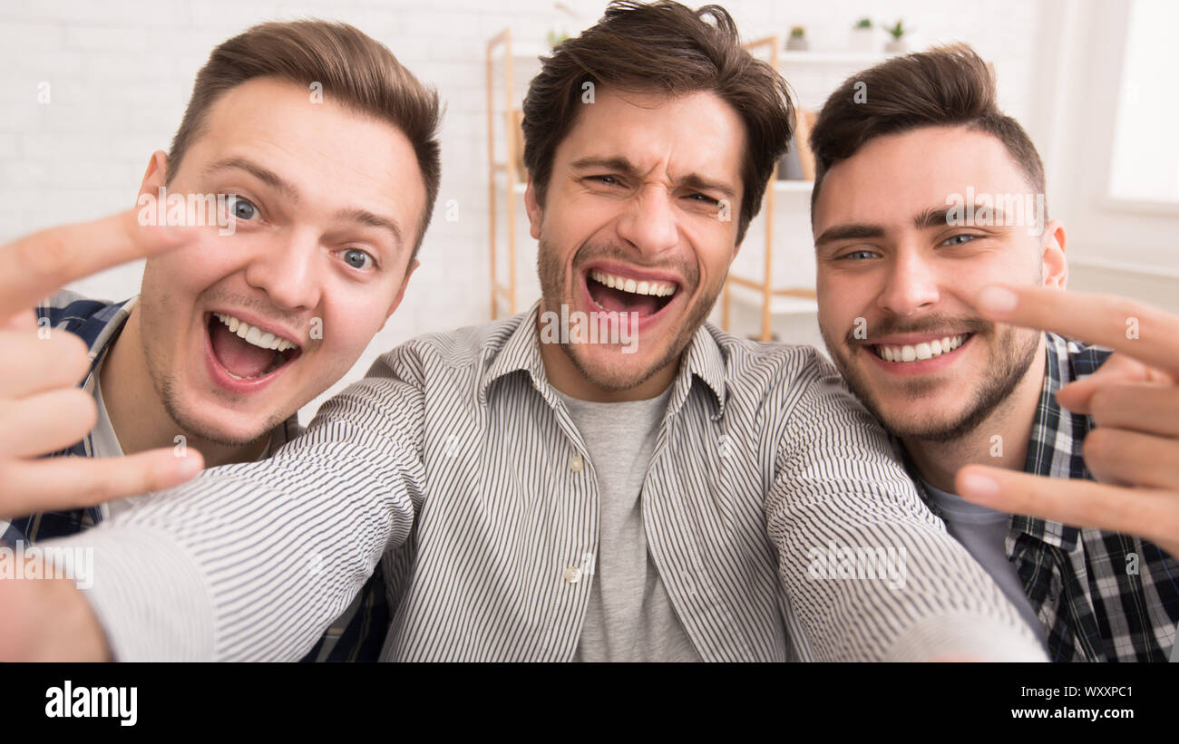 Happy guys gesturing rock and roll sign and shooting selfie Stock Photo ...