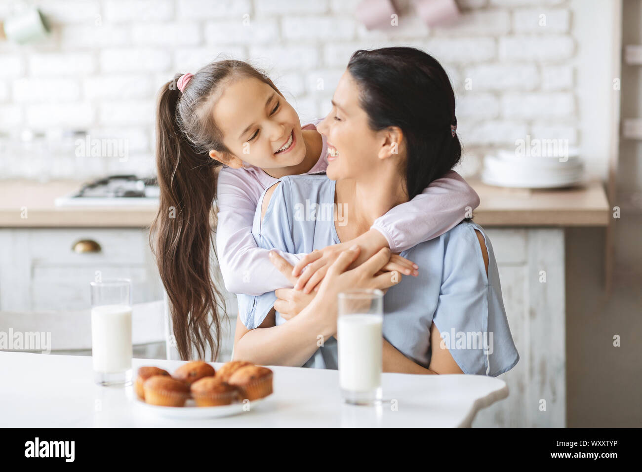 Happy family in kitchen. Daughter cuddling her mother from back Stock ...