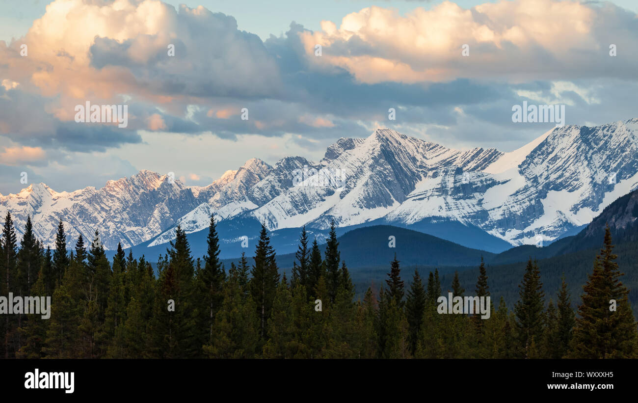 A moody sky at sunrise over a mountain range in Kananaskis Country ...