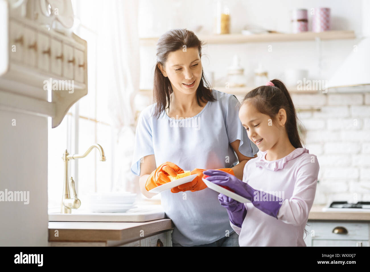Cute Teenage Girl Helping Mother Washing Dishes At Family Kitchen Stock ...