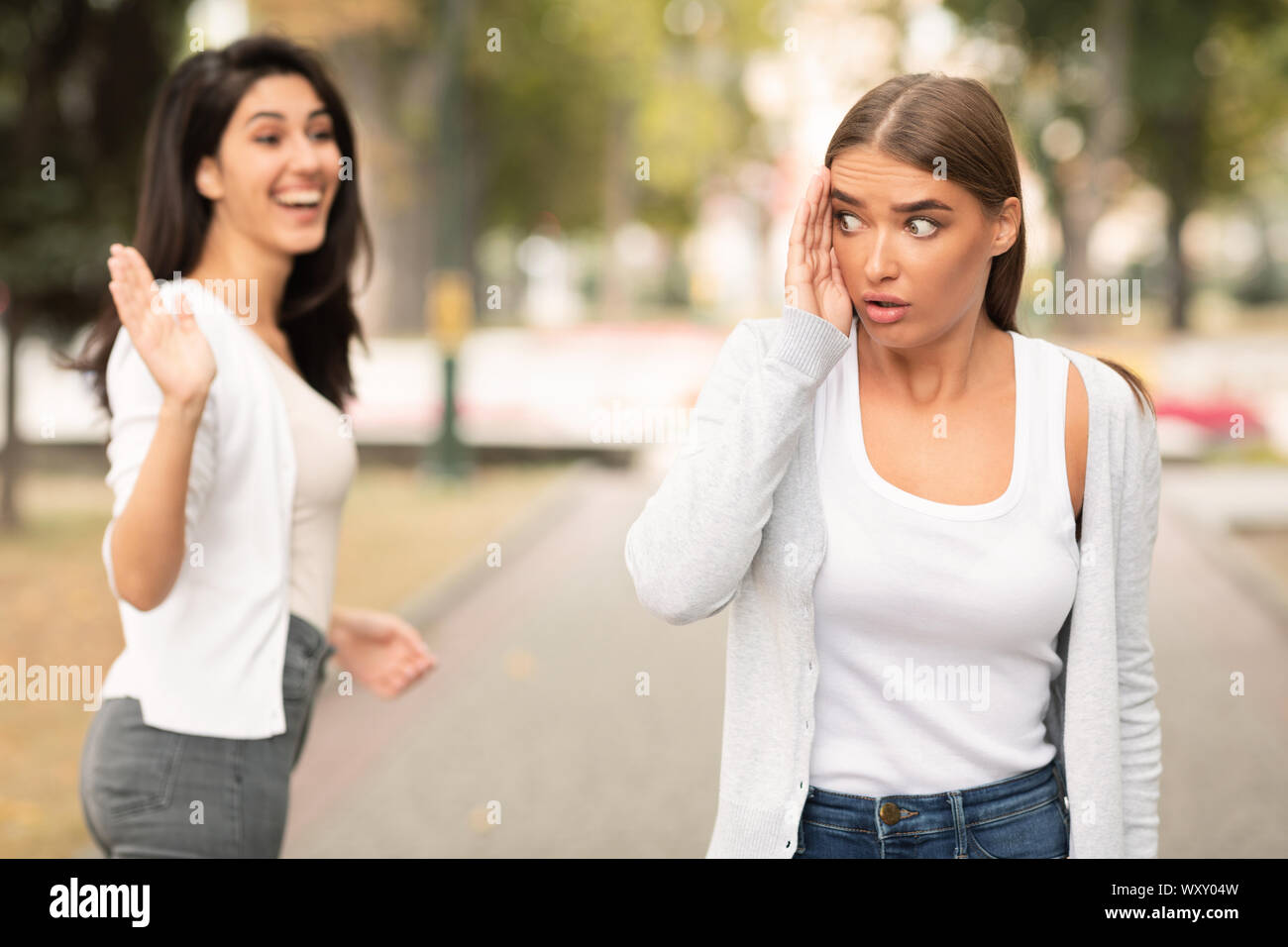 Happy girl greeting waving hand and friend ignoring her Stock Photo - Alamy