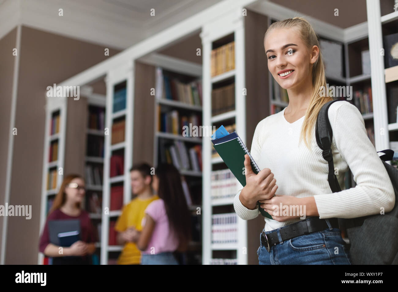 Pretty young girl smiling on library background Stock Photo - Alamy