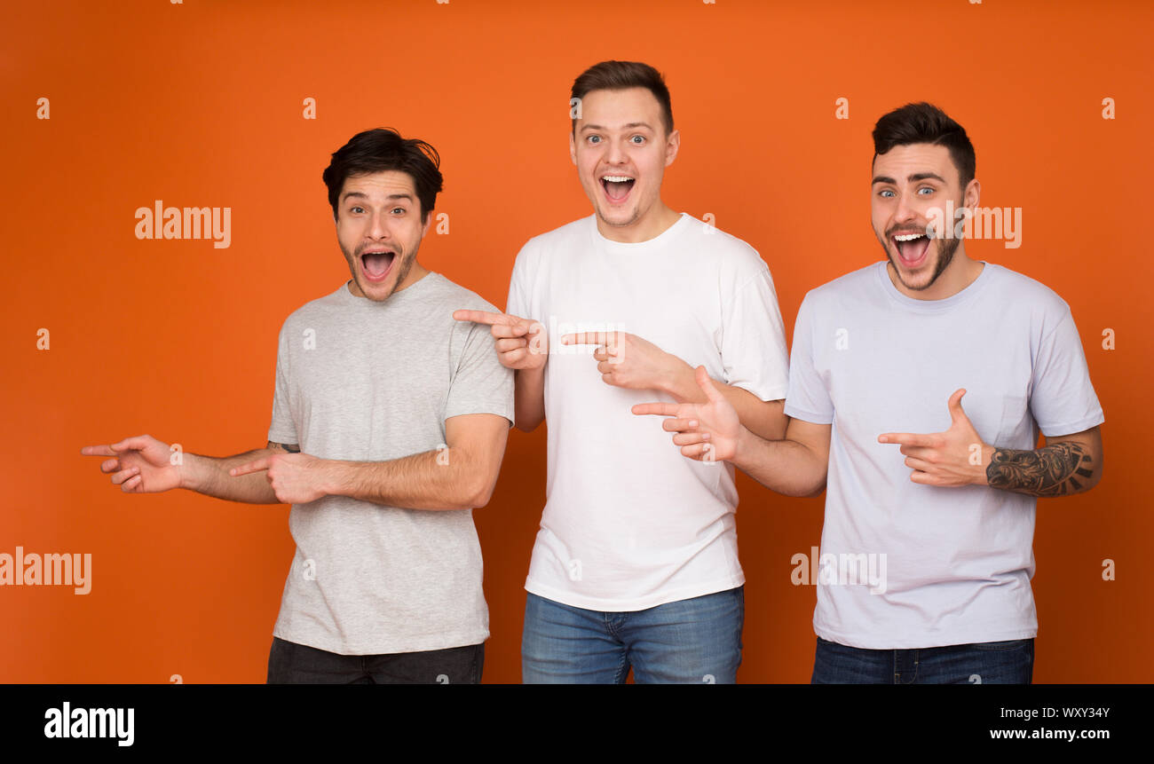 Surprised friends pointing fingers away, orange background Stock Photo ...
