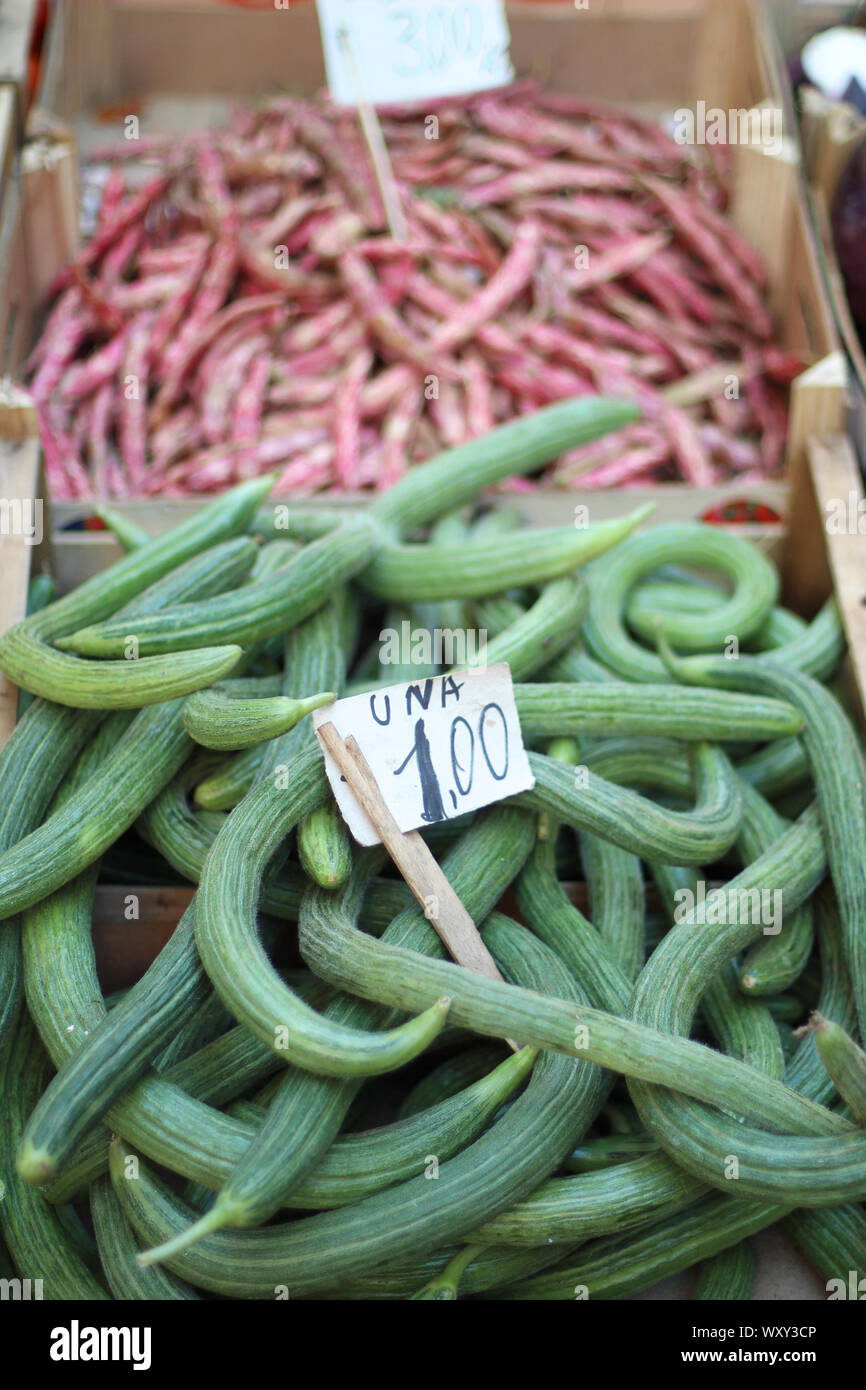 Fruits of exotic cucumber and red beans in boxes on the market counter ...