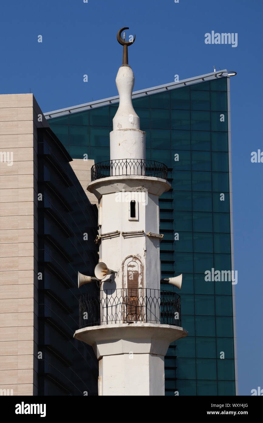 White minaret of a an old mosque with crescent is contrasted against ...
