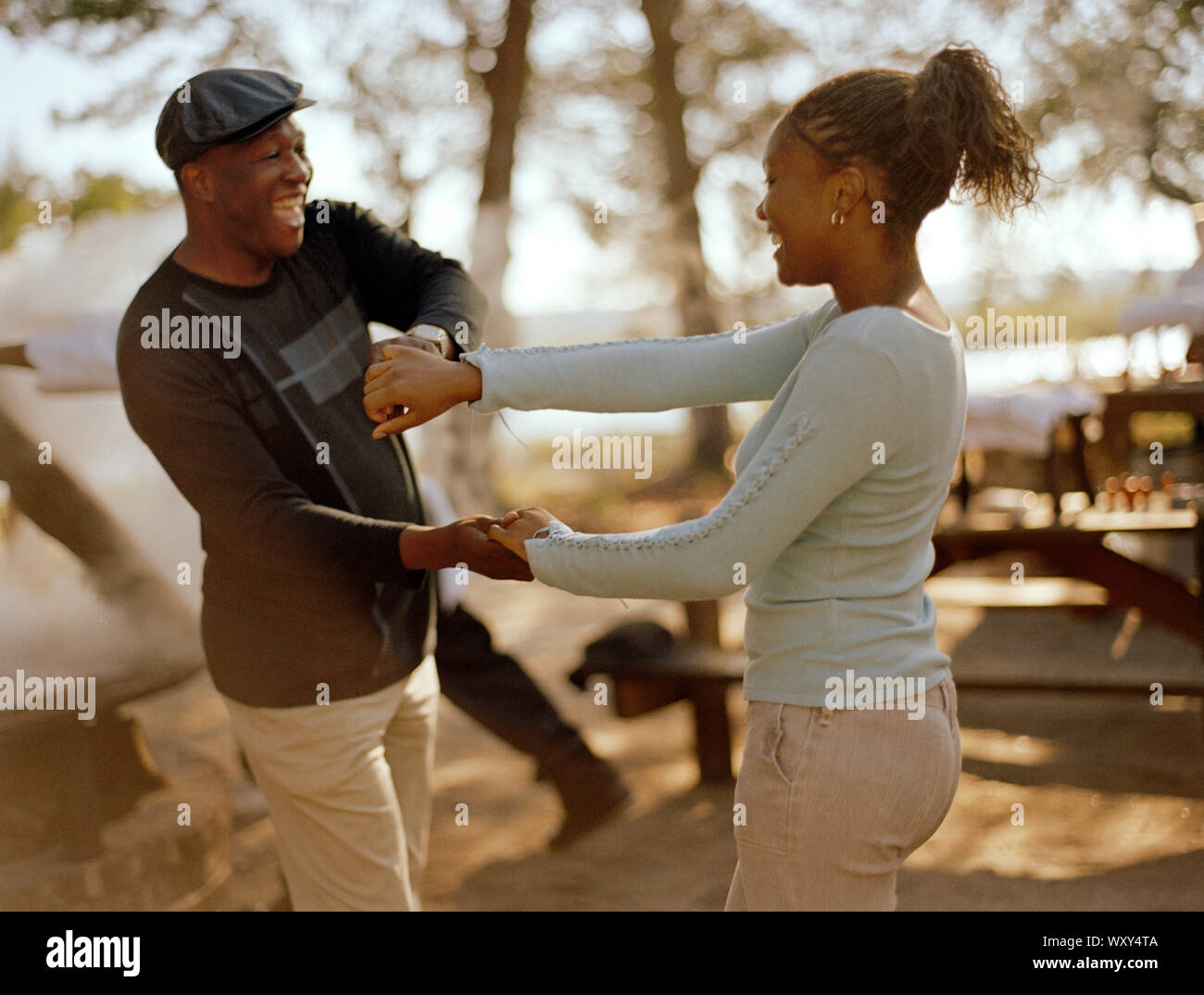 Young couple holding hands while dancing playfully together Stock Photo ...