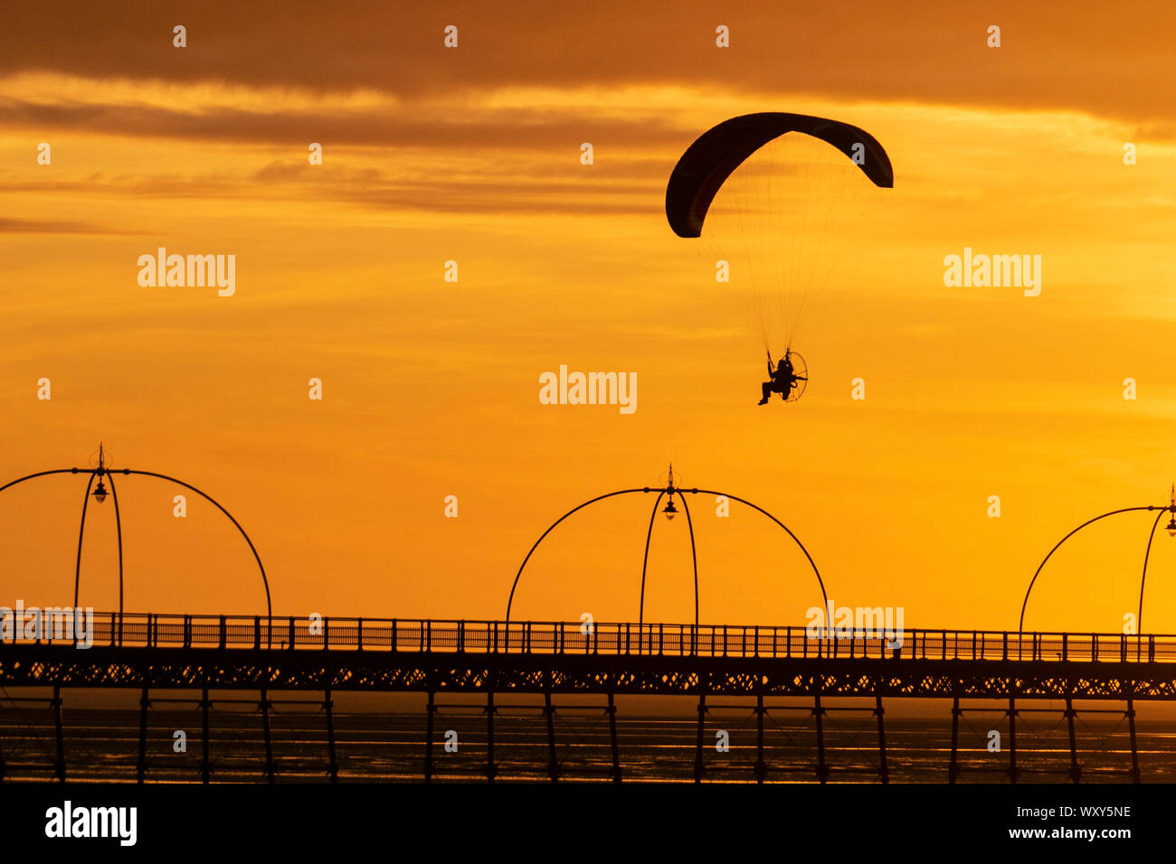 Powered hand glider silhouetted in the evening sun, takes a motorized ...