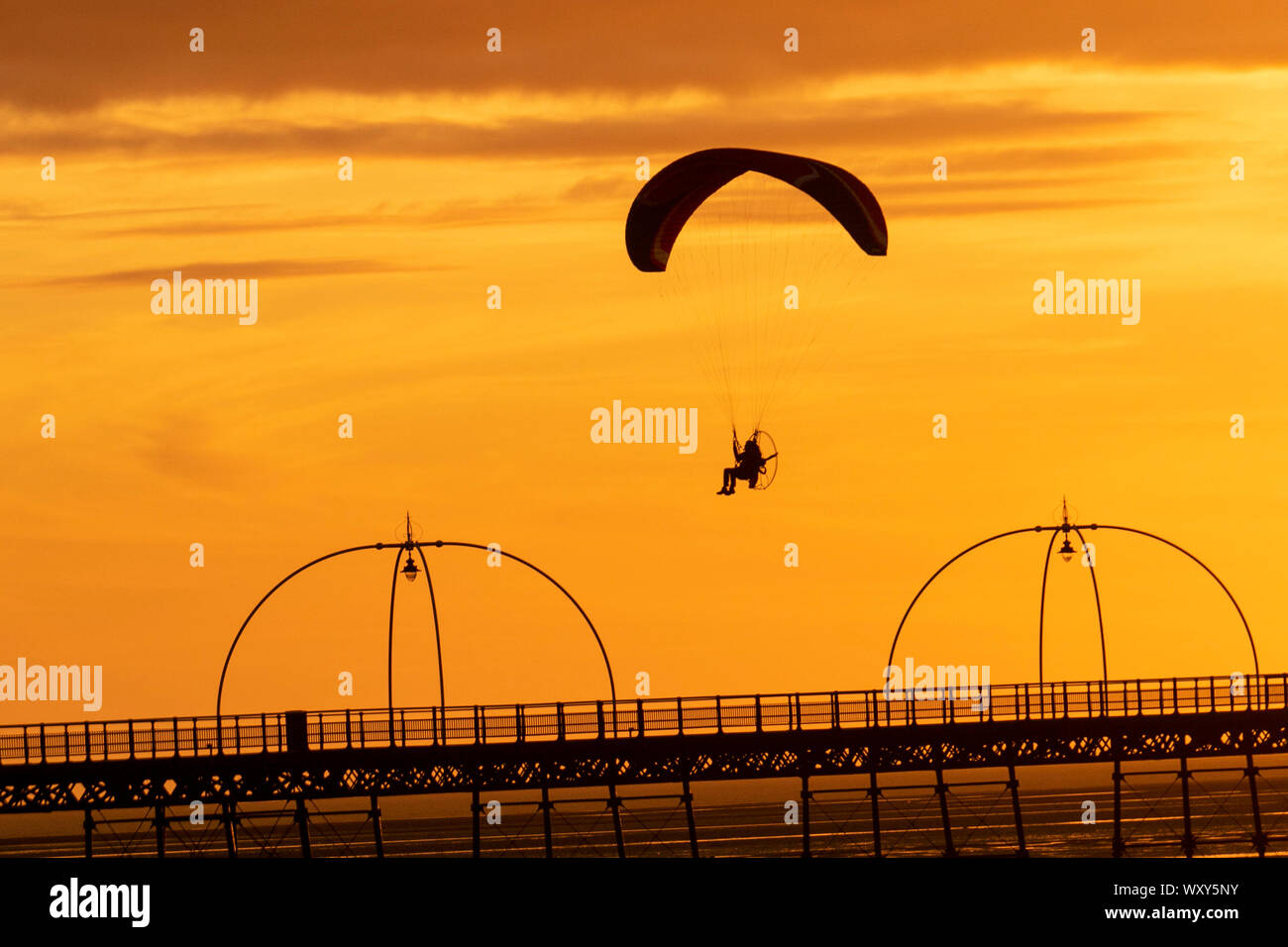 Powered hand glider silhouetted in the evening sun, takes a motorized ...
