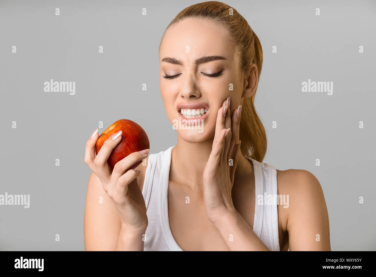 Tooth problems. Young woman having toothache, biting apple Stock Photo ...
