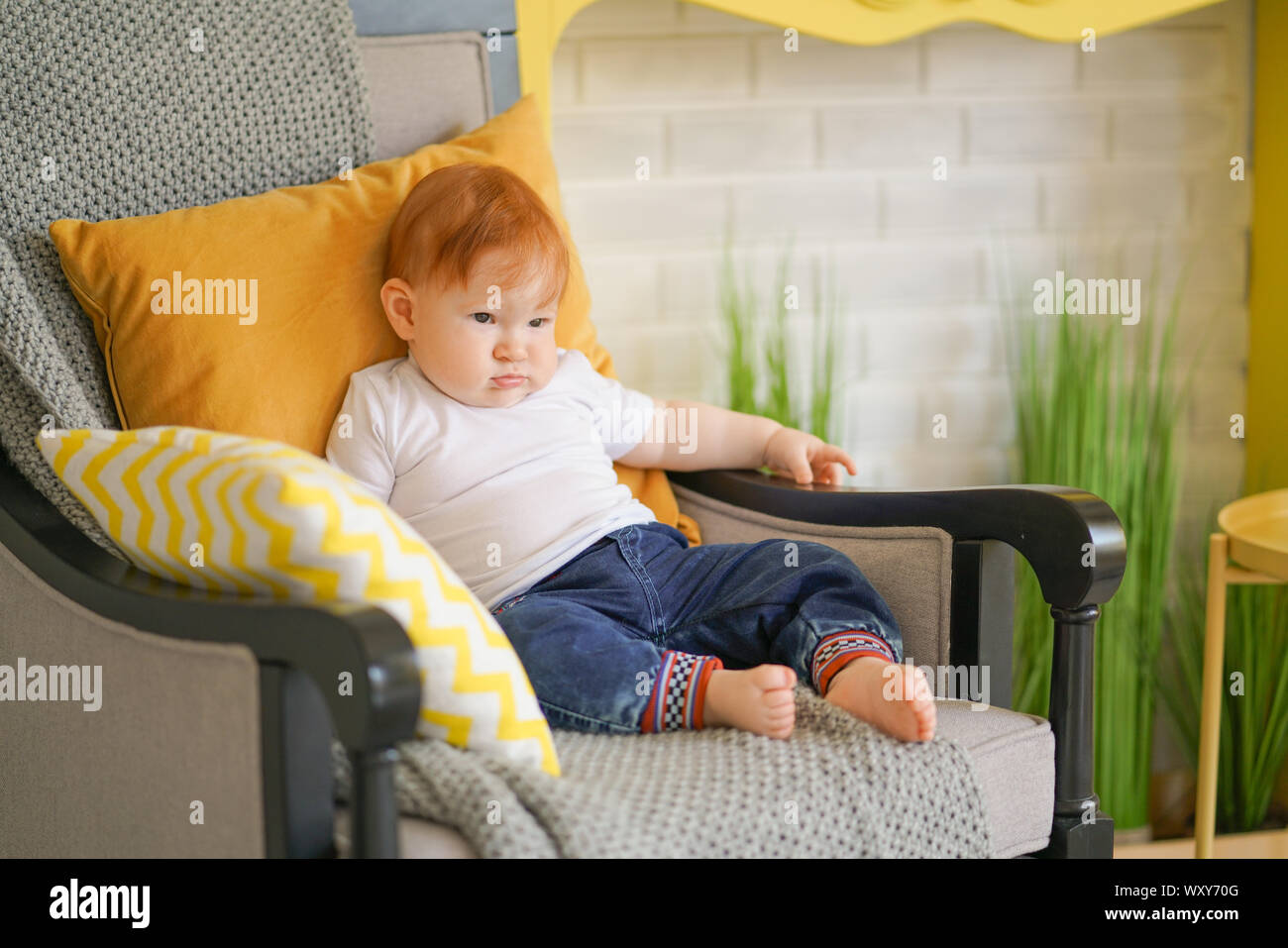 small child sits in a chair and holds a pillow in his hands. the ...