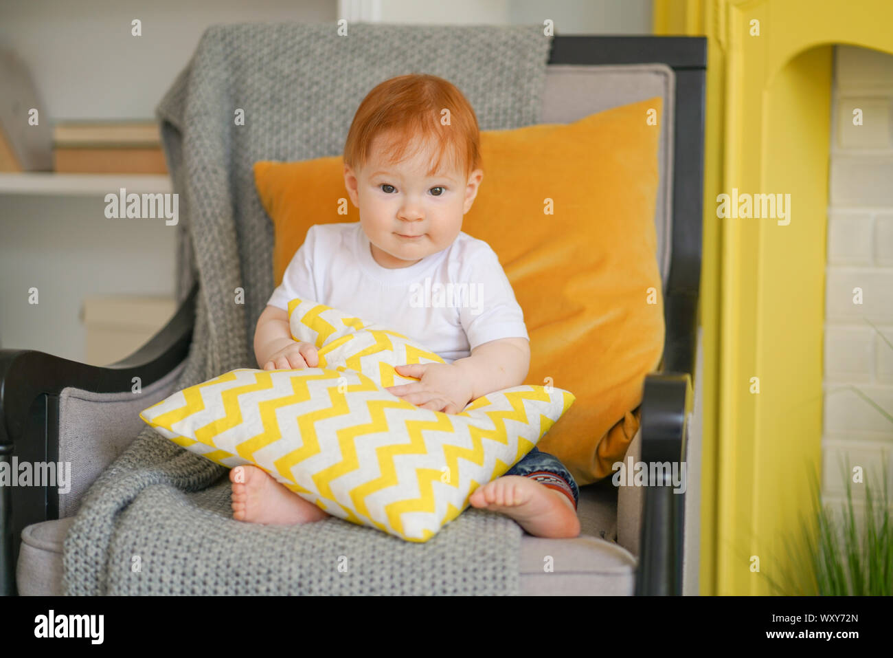 small child sits in a chair and holds a pillow in his hands. the ...