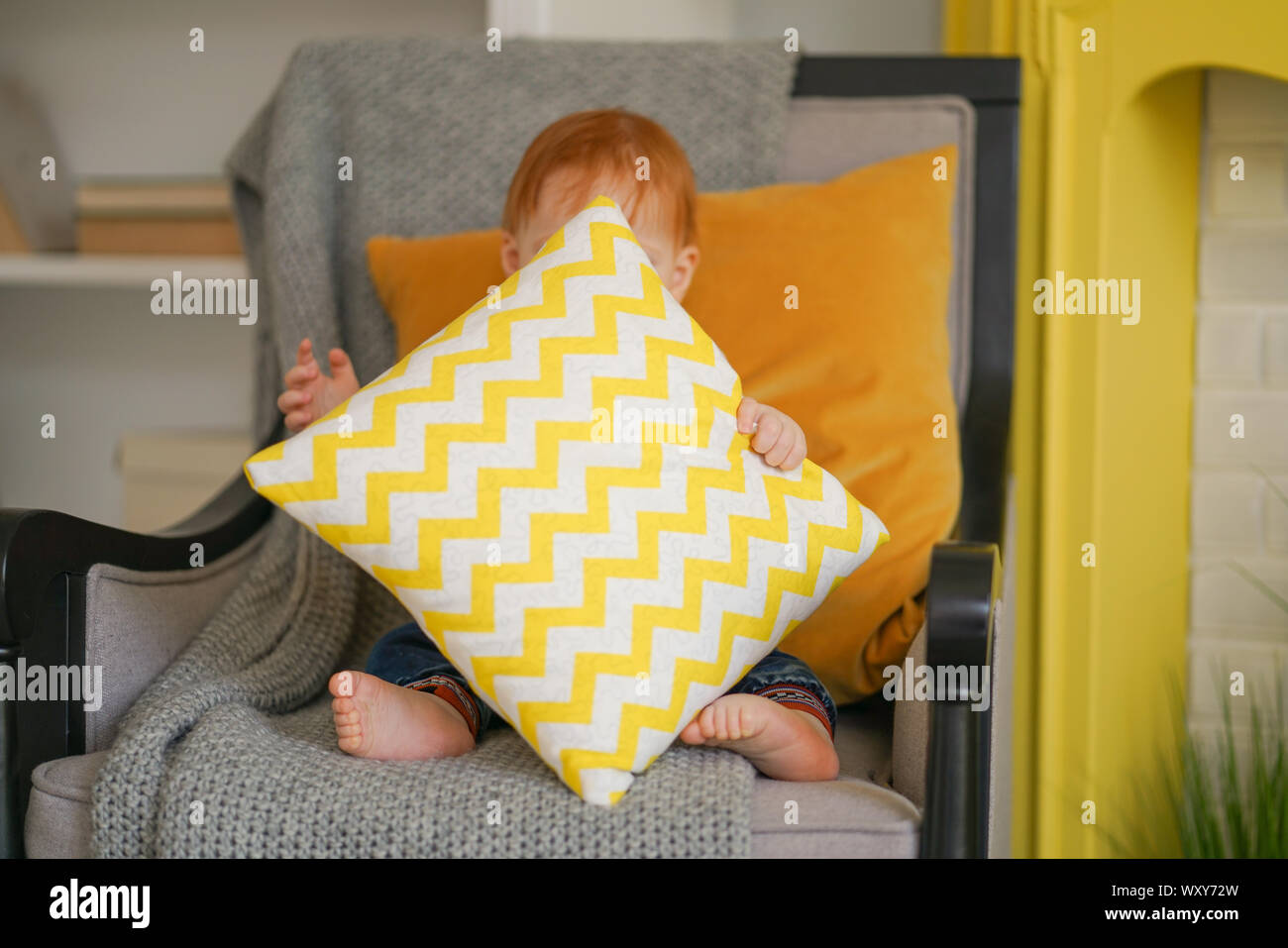 small child sits in a chair and holds a pillow in his hands. the ...