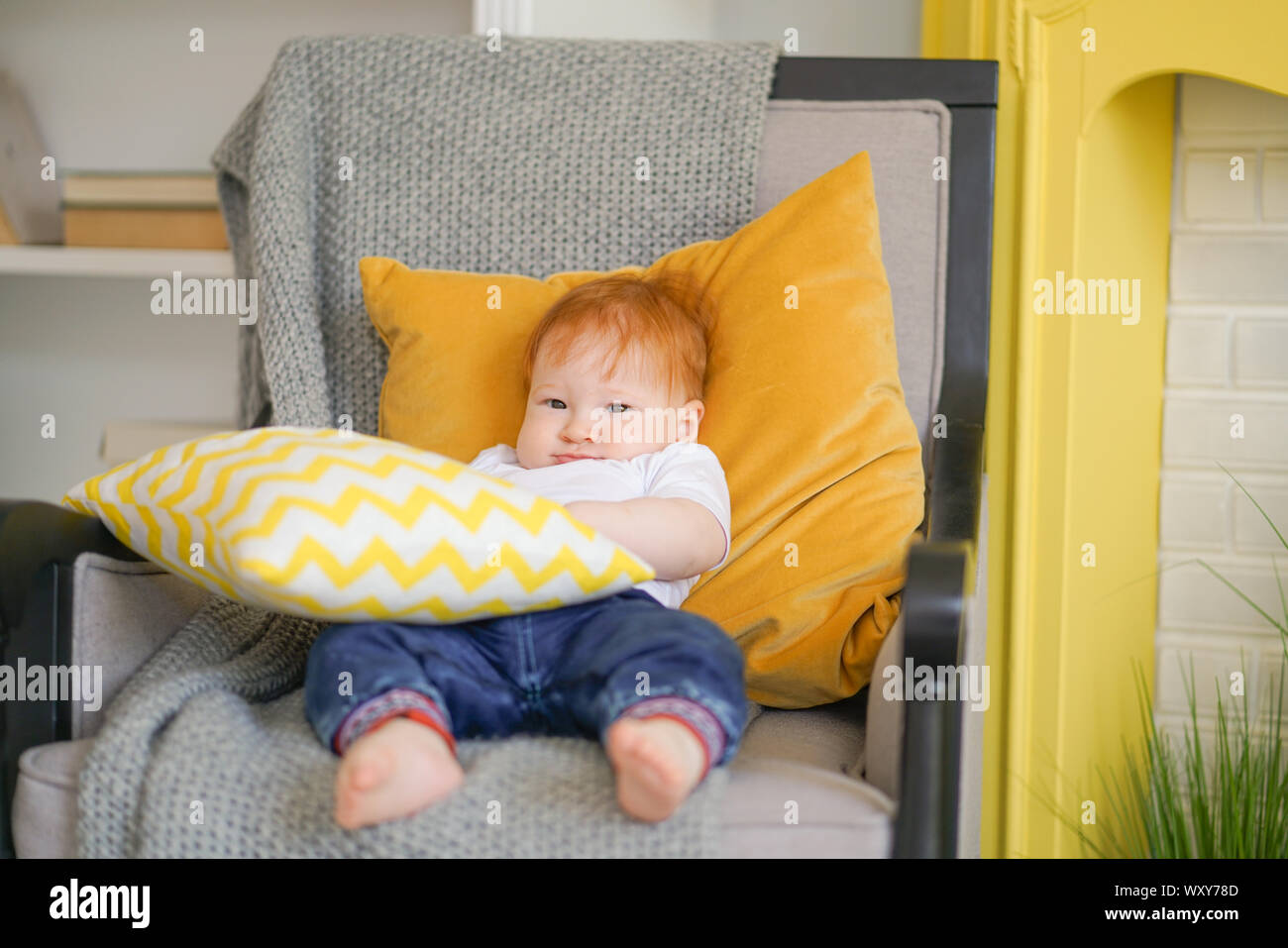small child sits in a chair and holds a pillow in his hands. the ...