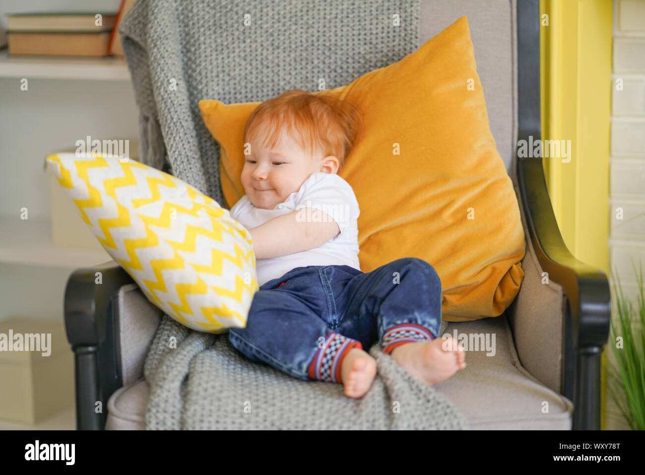 small child sits in a chair and holds a pillow in his hands. the ...