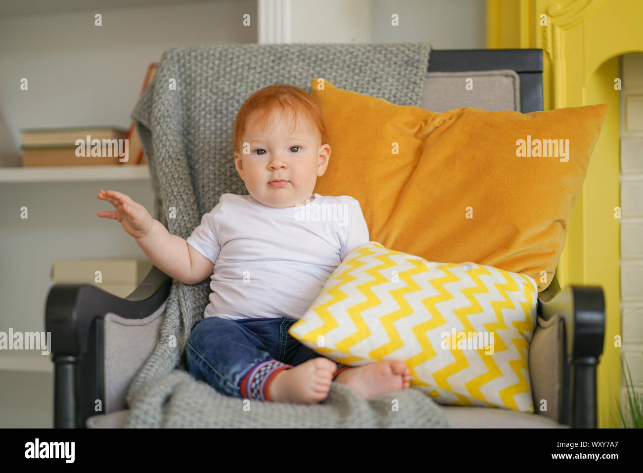 small child sits in a chair and holds a pillow in his hands. the ...