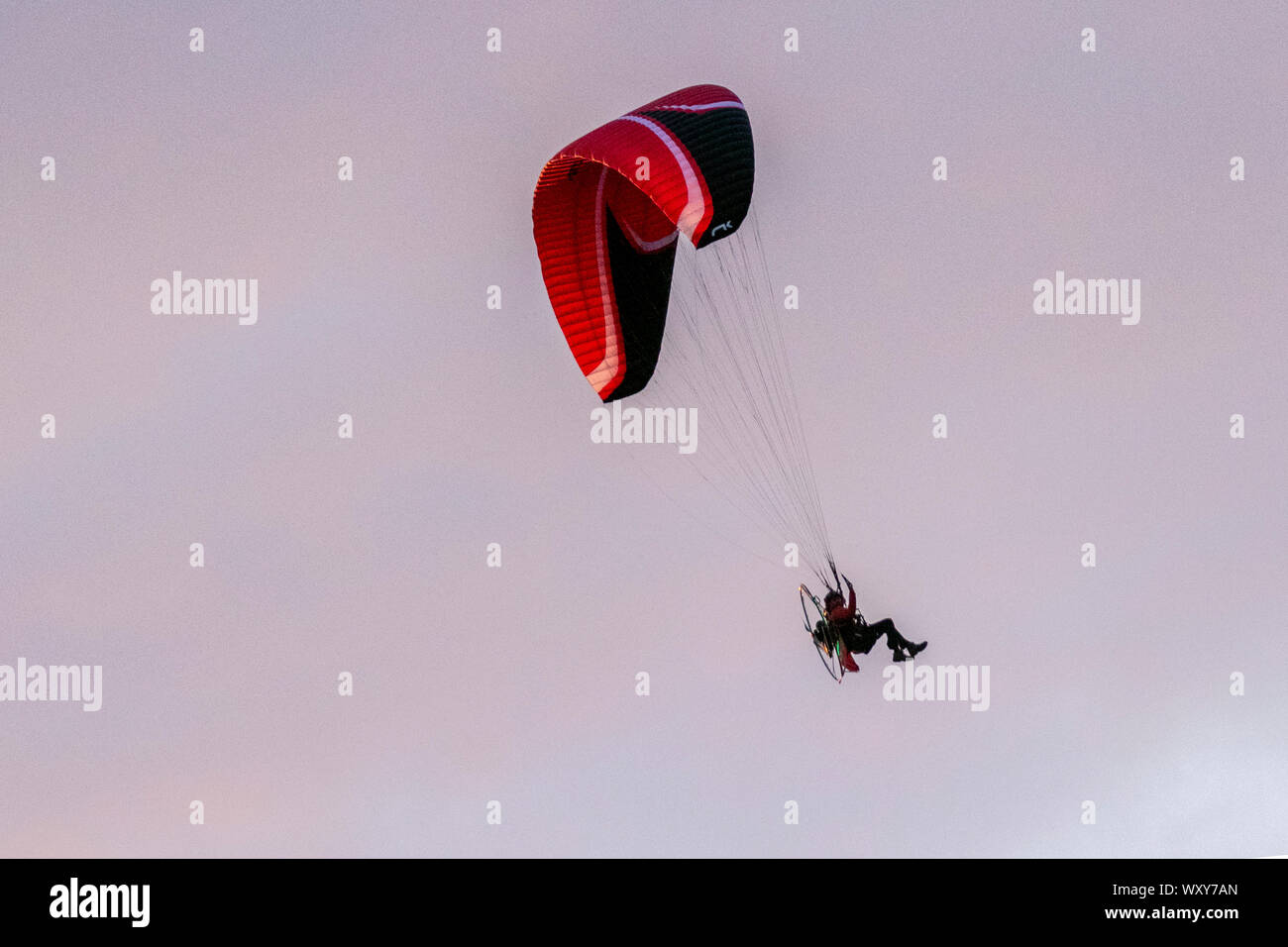 Powered hand glider silhouetted in the evening sun, takes a motorized ...