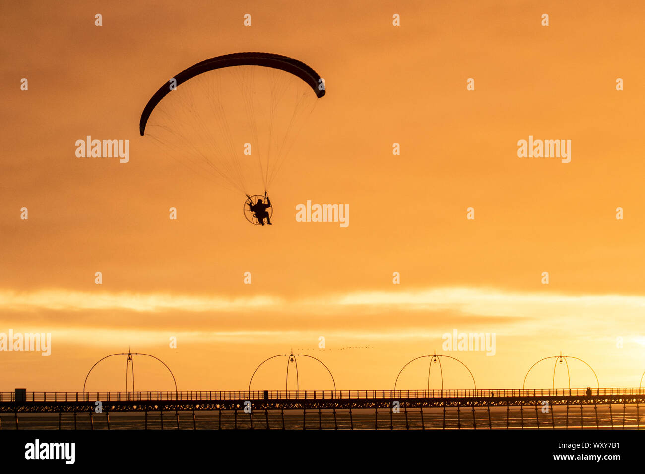 Powered hand glider silhouetted in the evening sun, takes a motorized ...