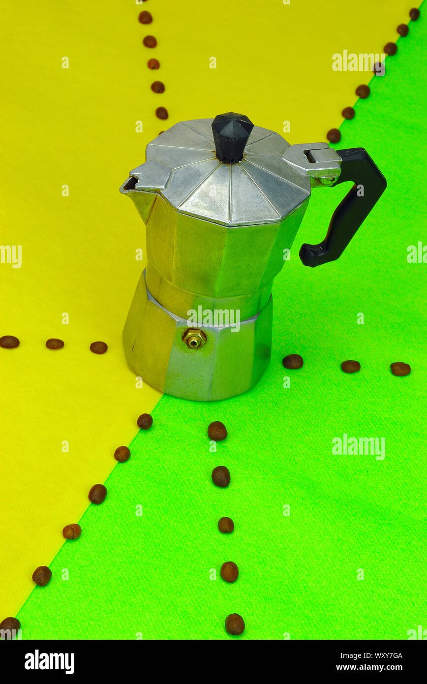 small traditional italian coffee pot on green and yellow background ...