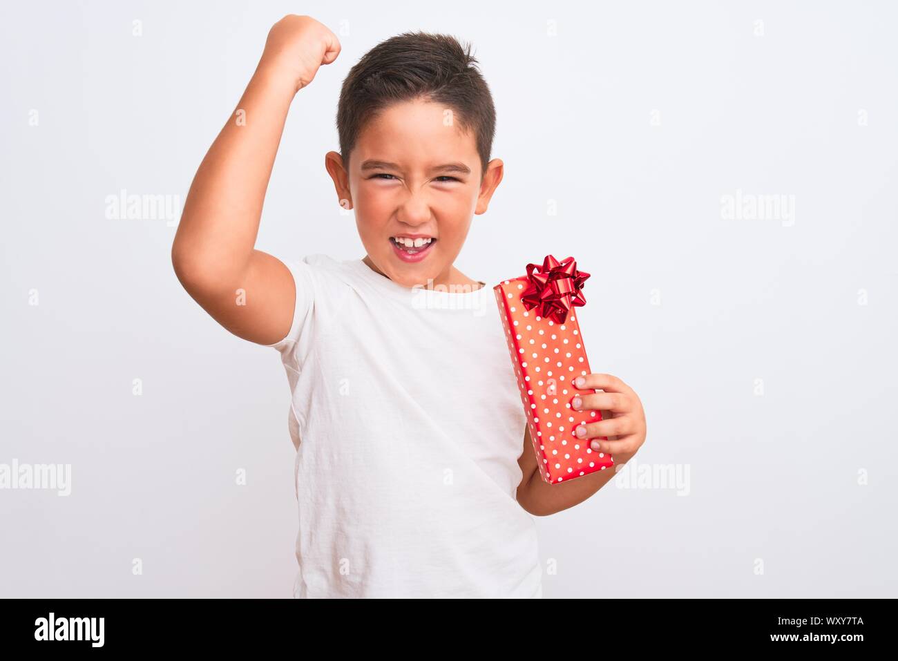 Beautiful kid boy holding birthday gift standing over isolated white ...