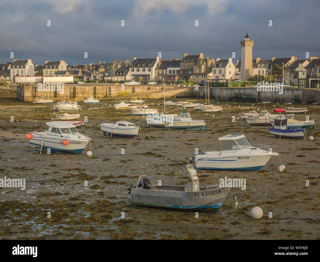 Many small boats sitting in mud at low tide in the harbor at Roscoff ...