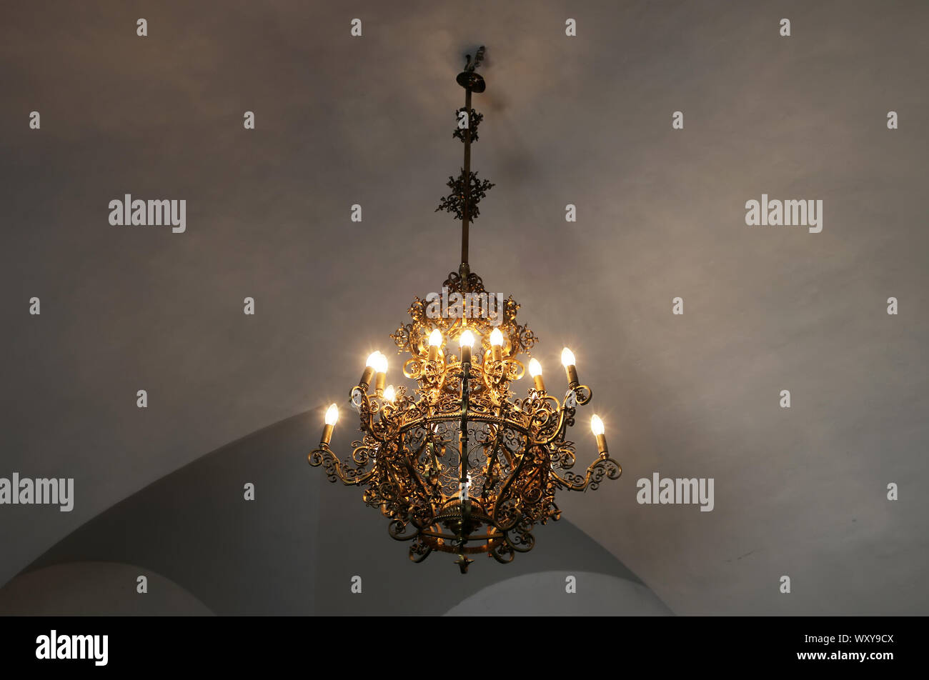 Old medieval chandelier with modern light bulbs in old castle. Concept ...
